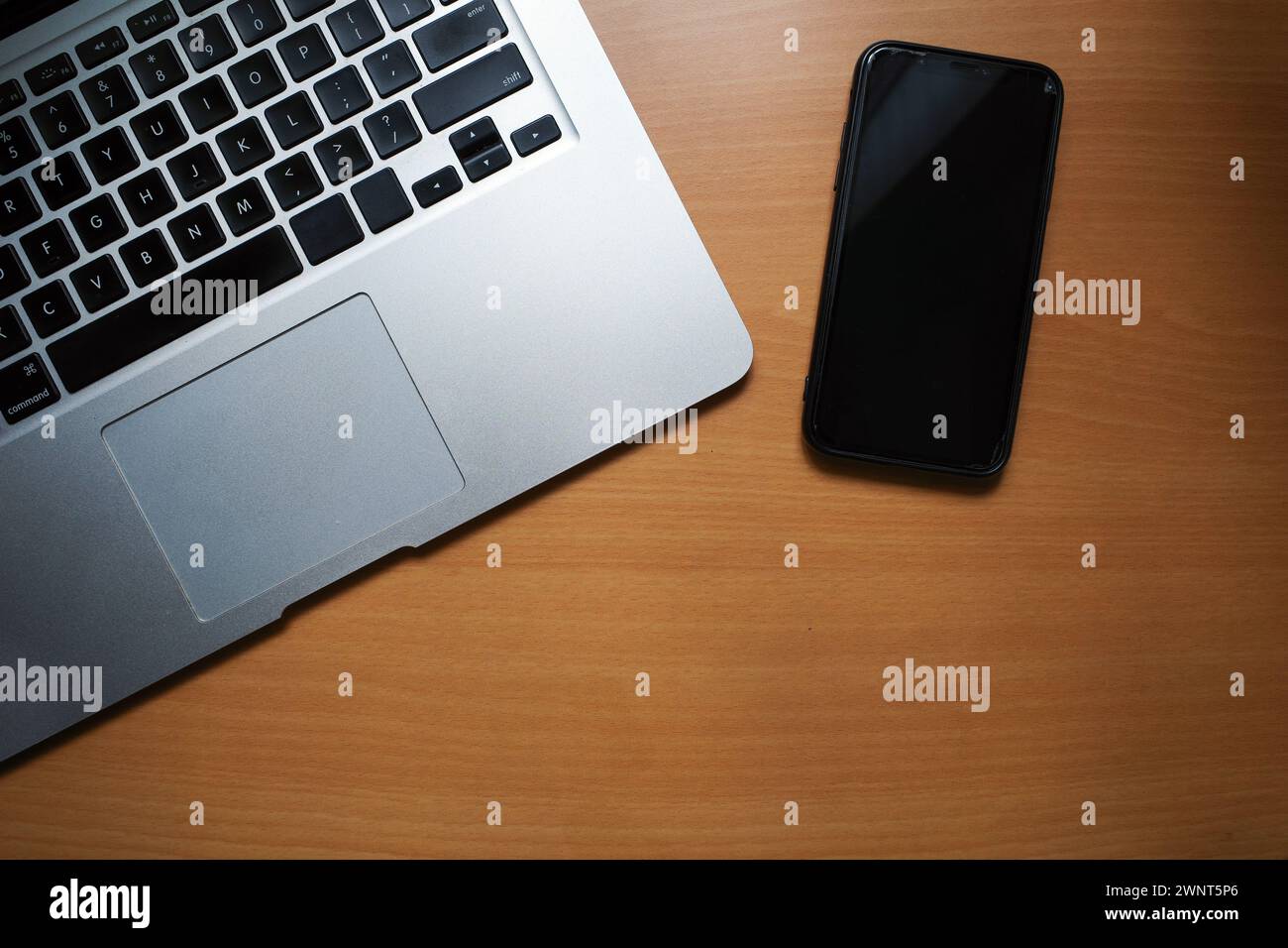 A business desk table with a laptop and a smartphone. Wood background ...