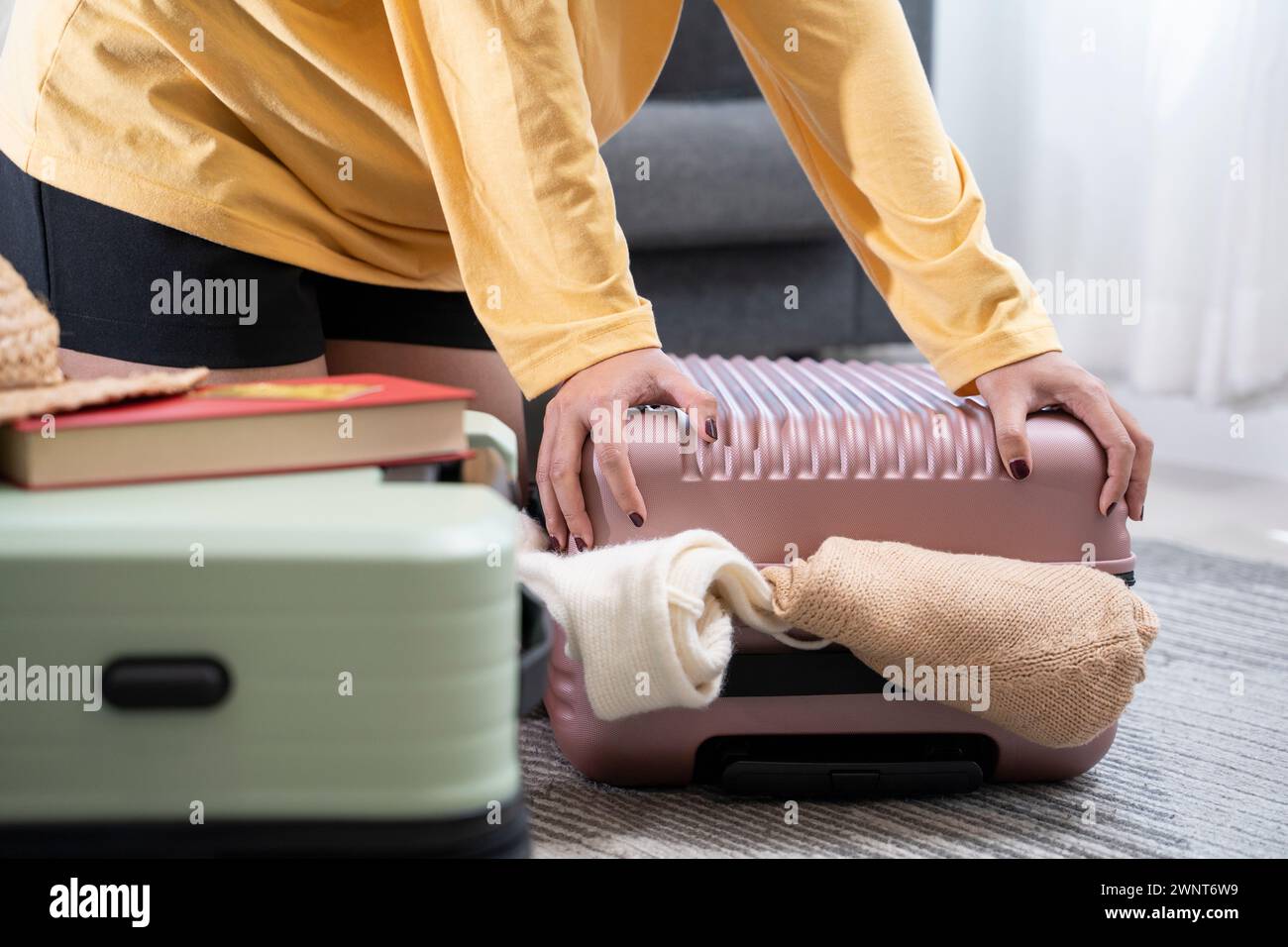Asian young woman stacking clothes and into bag case, trying to pack ...