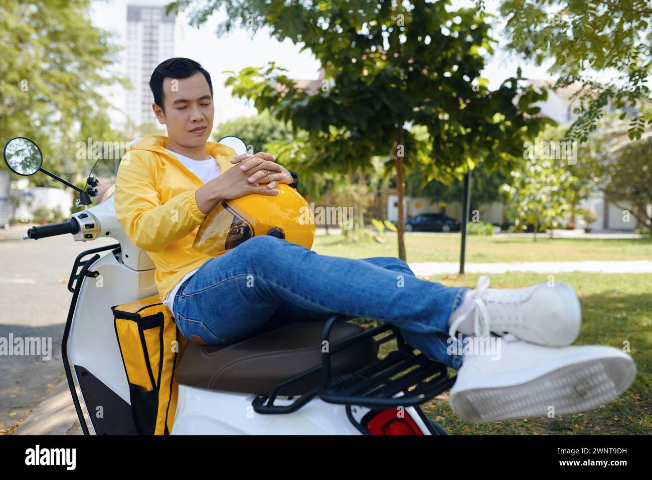 Tired delivery man on scooter hi-res stock photography and images - Alamy