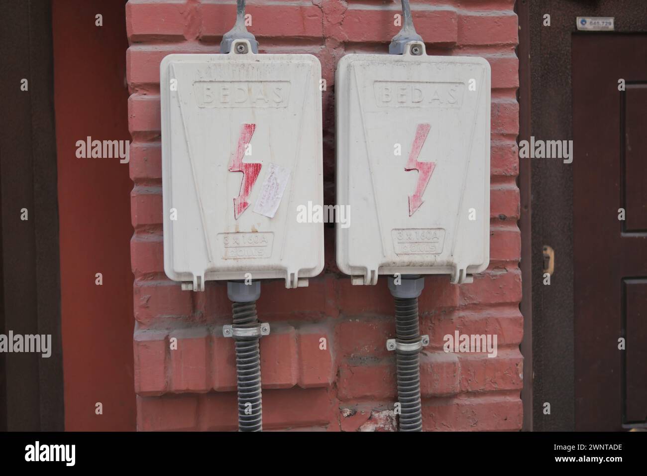 Two electrical boxes with lightning bolt on brick wall Stock Photo - Alamy