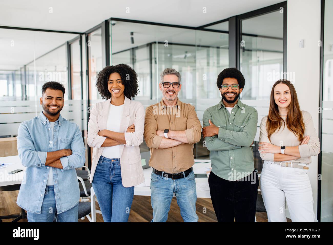 A vibrant team of five professionals stands with confidence in office ...