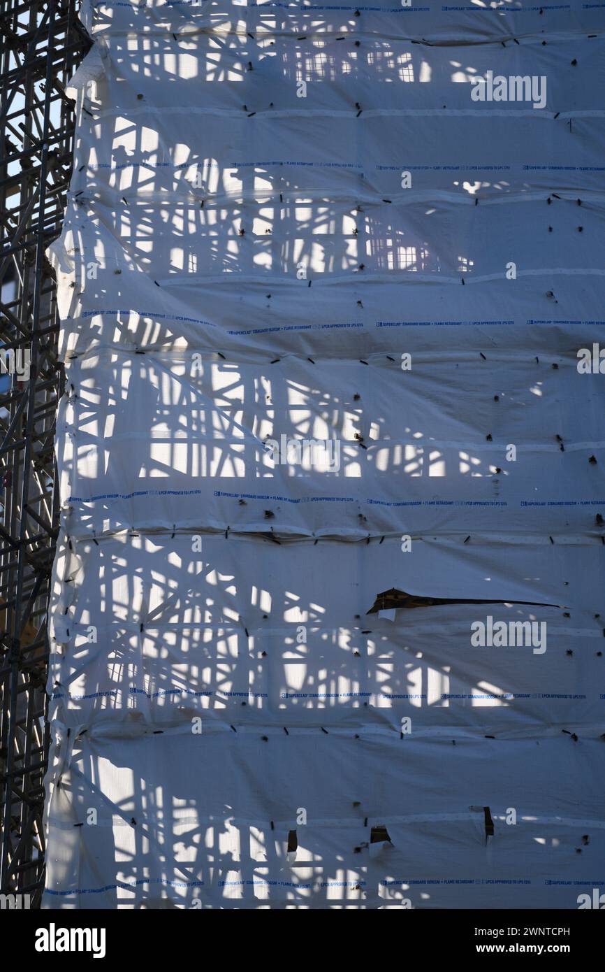 The silhouette of scaffolding cast on the protective net covering a ...