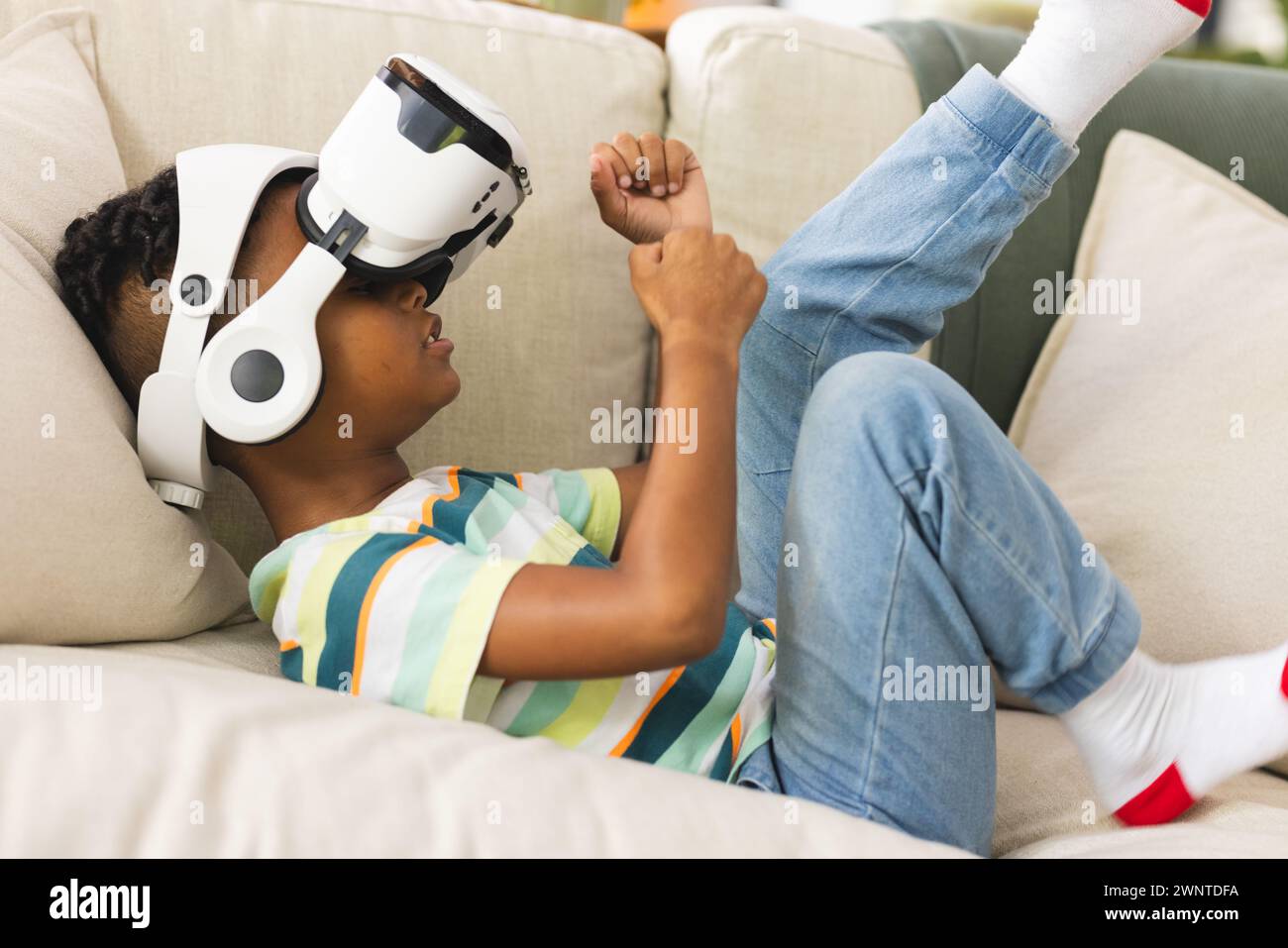 African American boy enjoys a virtual reality headset, lying back on a ...