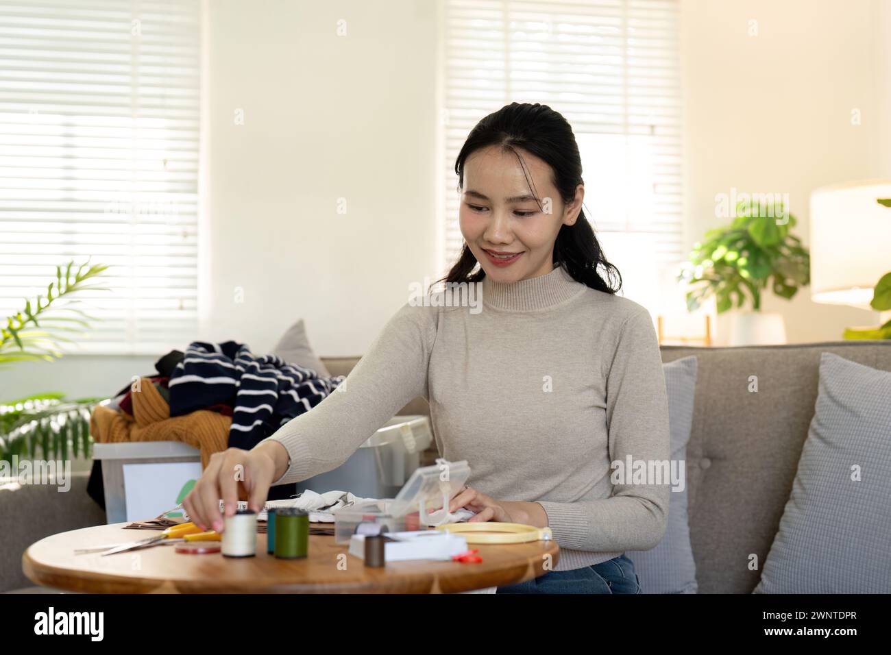 Woman repairs sews reuses fabric from old clothes economical reuse. DIY ...