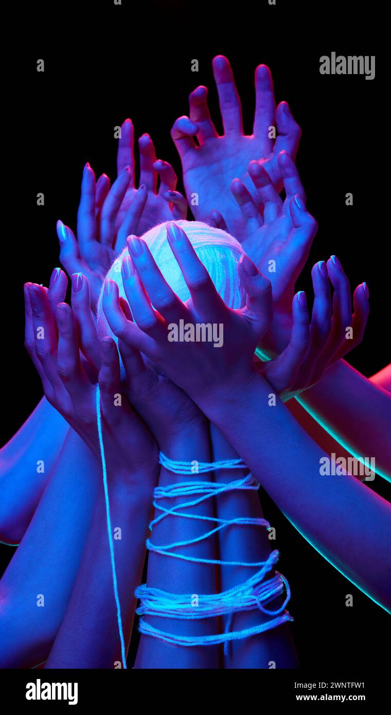 Hands encircle glowing ball of threads in multicolored neon lighting ...