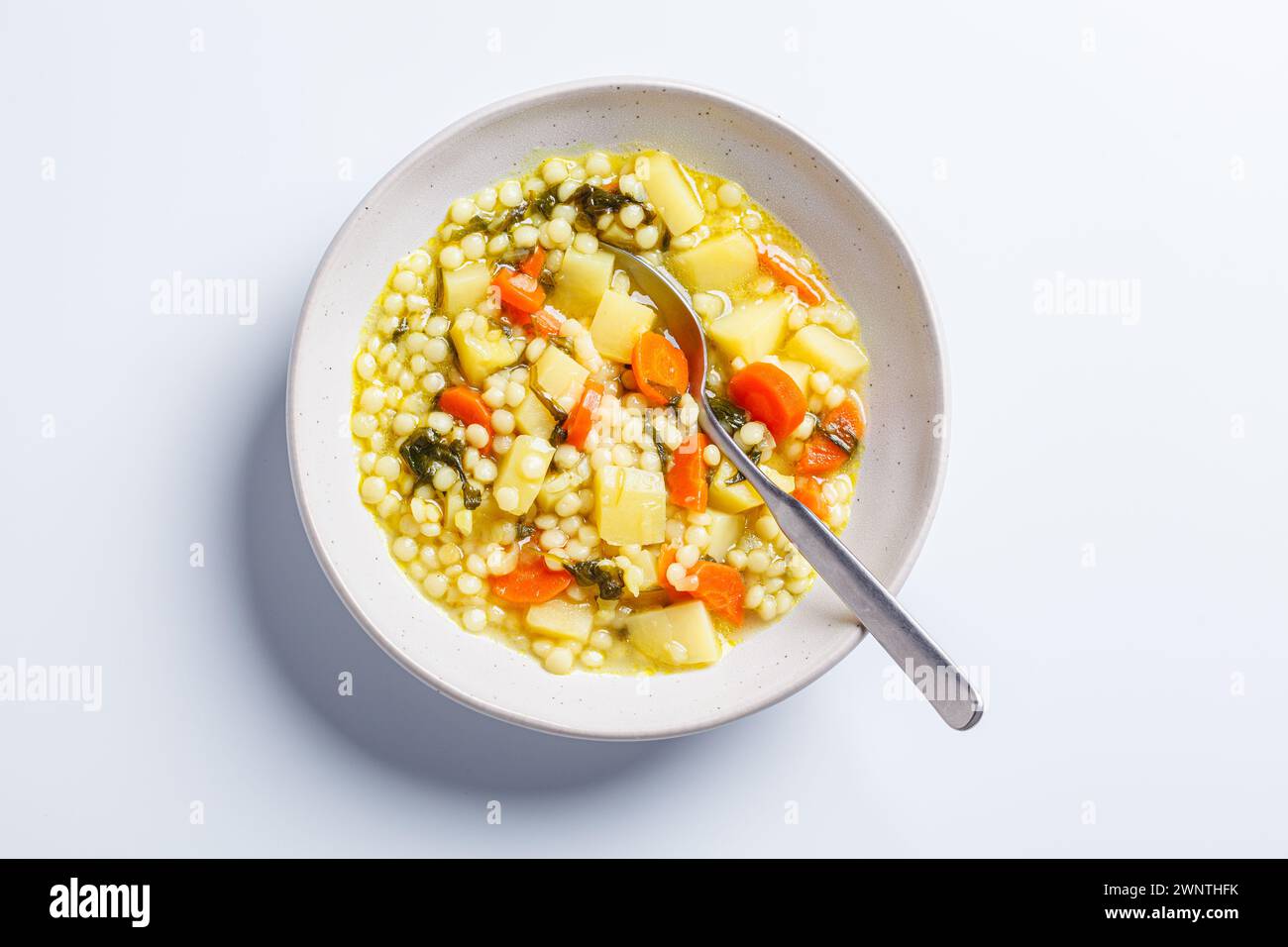Traditional Israeli soup with ptitim, vegetables and spinach, top view ...