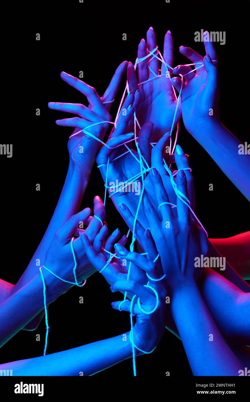 Hands interact with luminescent threads in multicolored neon lighting ...