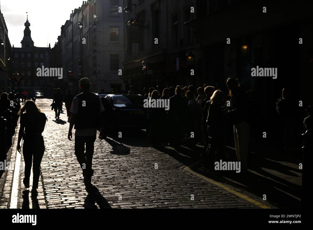 Silhouetted outside the Coach and Horses Pub are pedestrians and ...