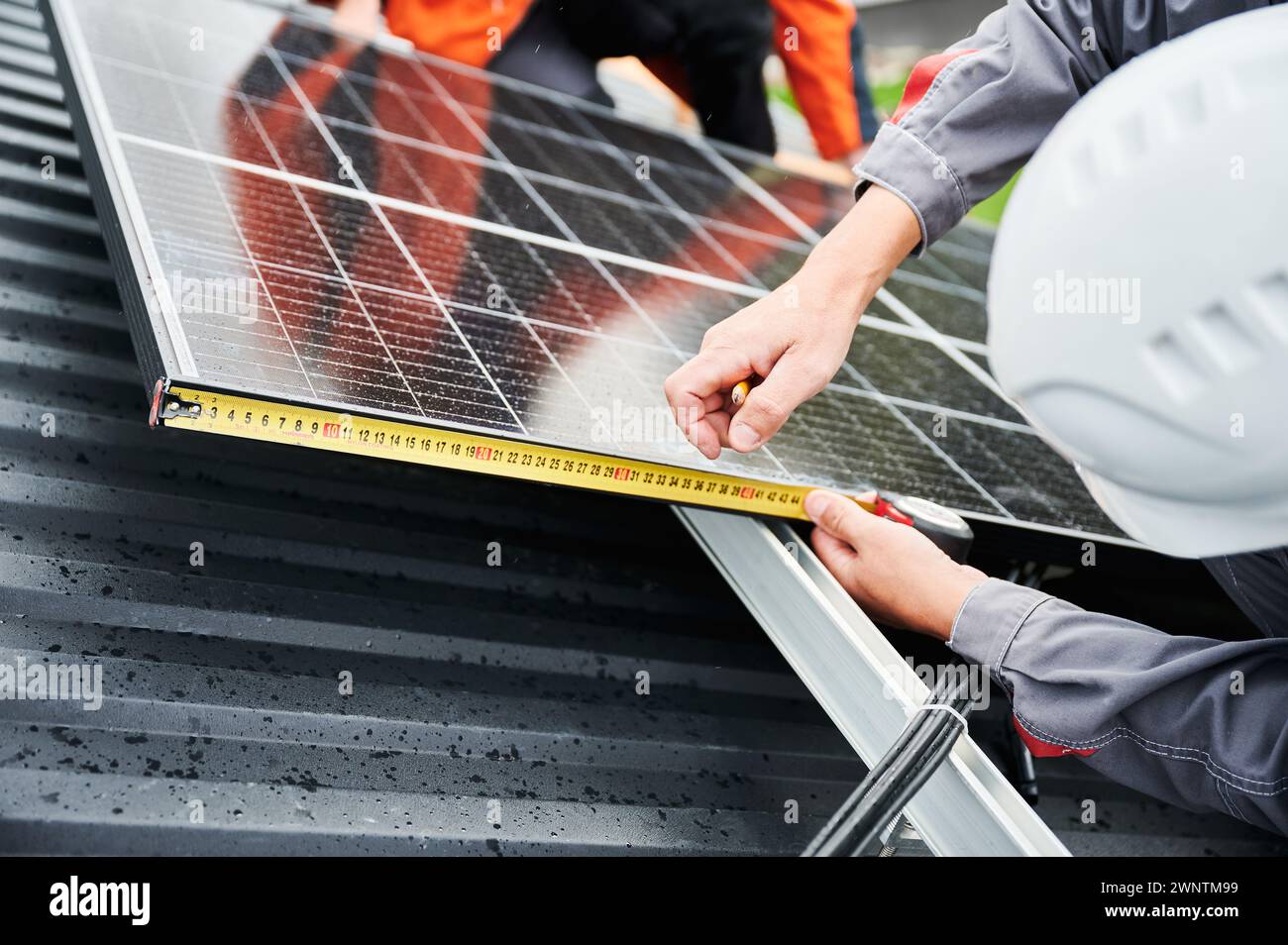 Man measuring photovoltaic solar panels with tape measure. Close up ...