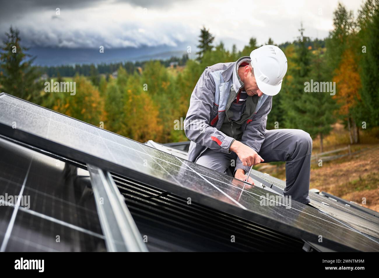 Man mounter mounting photovoltaic solar panels on roof of house ...