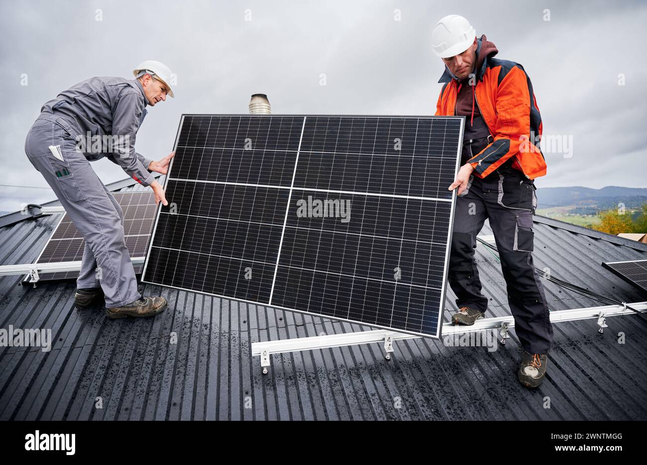 Engineers building solar panel system on roof of house. Men workers in ...