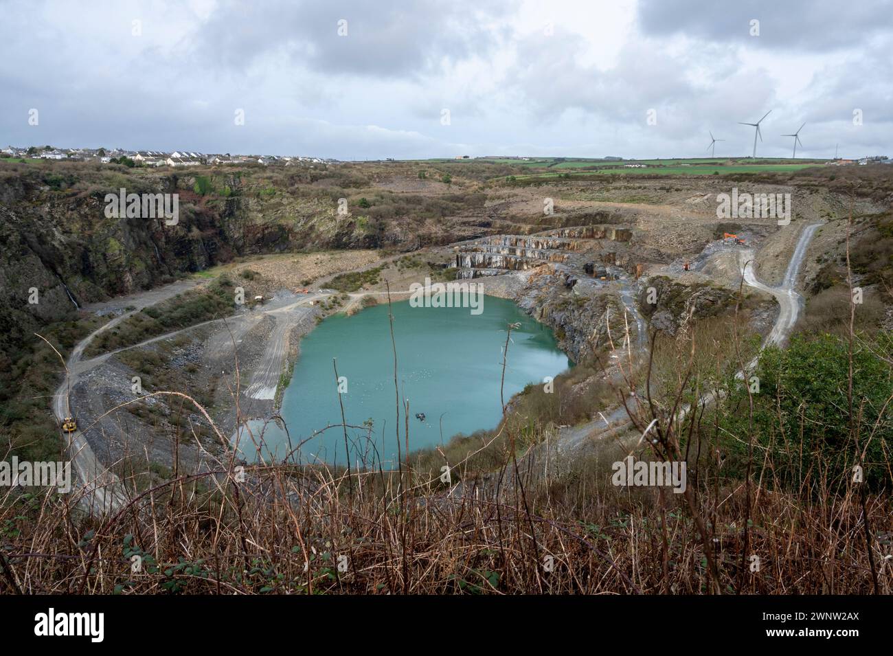Delabole slate quarry with mining diggers and trucks. Above is the ...