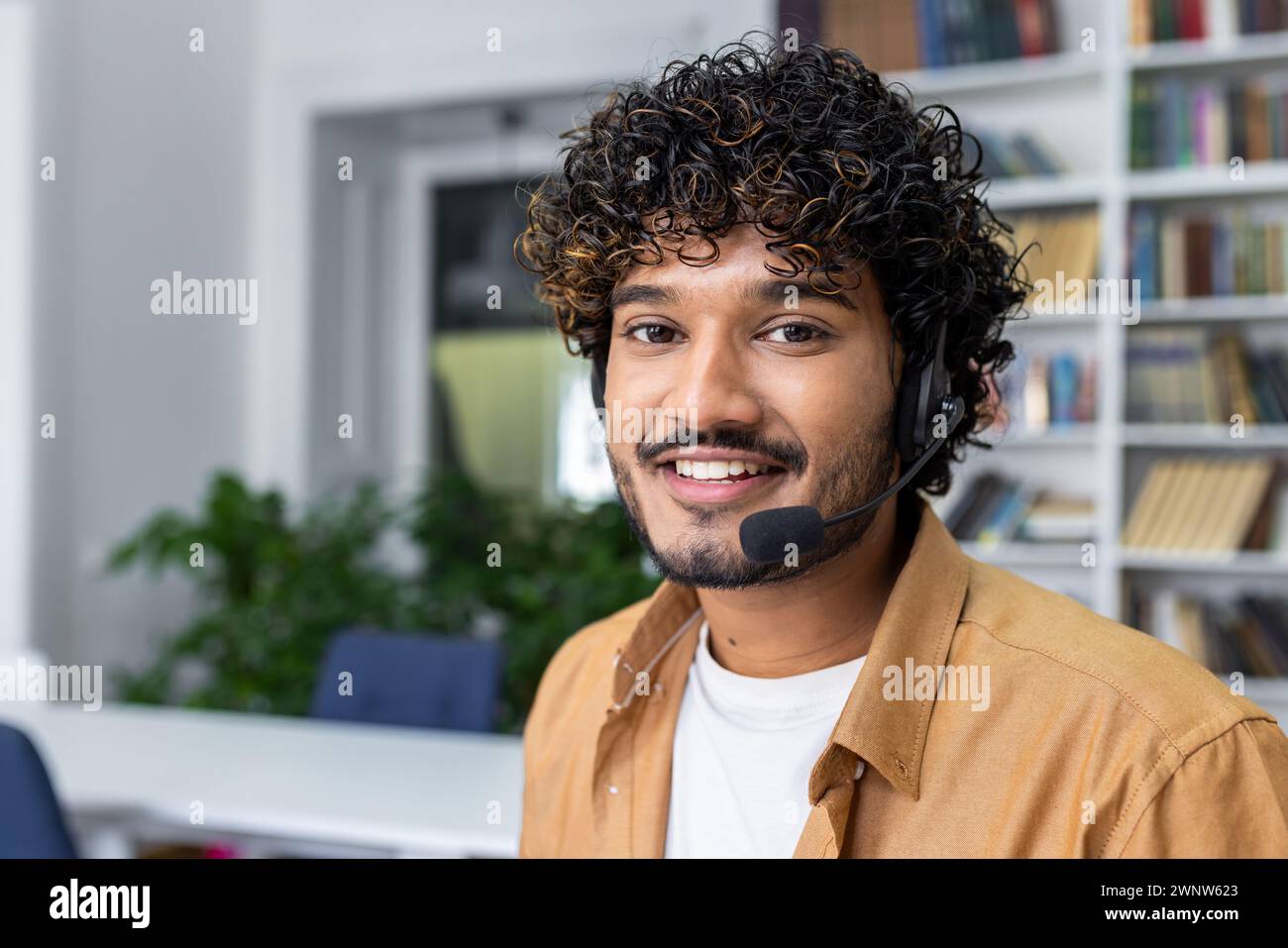 A cheerful customer service representative wearing a headset in a modern office setting. This ...