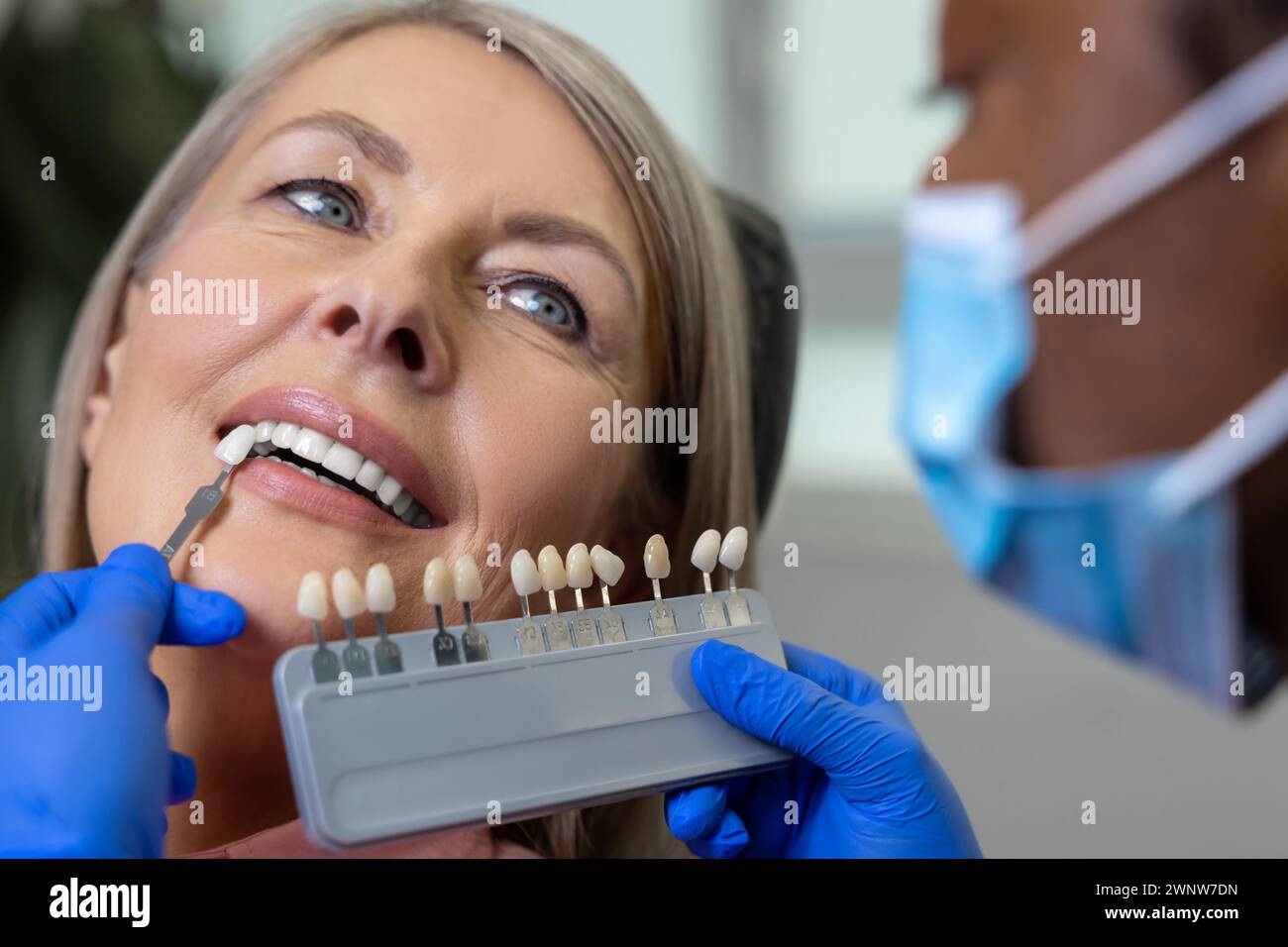 Woman patient with doctor orthodontist choosing the shade of dental ...