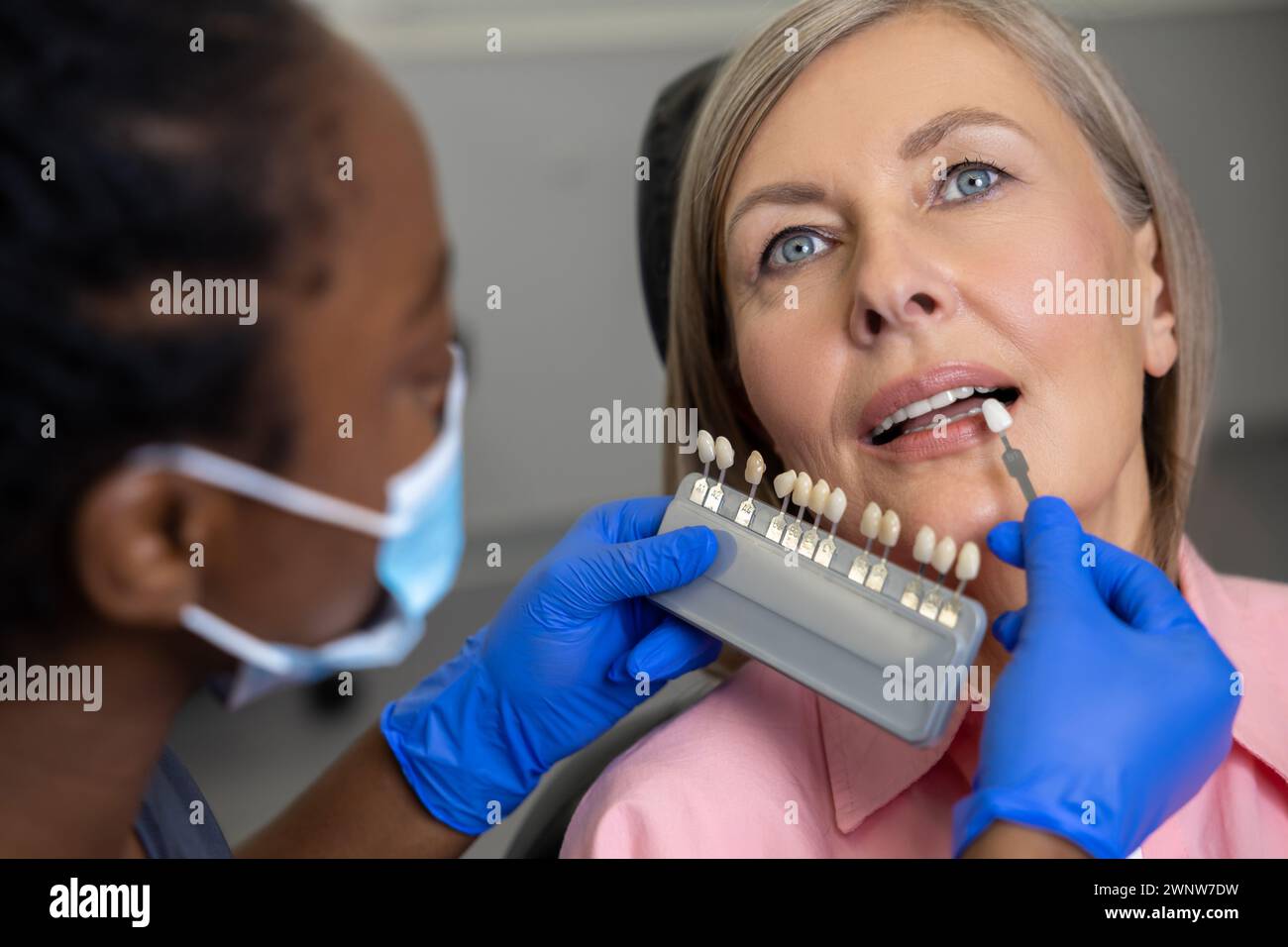 Woman dentist holding dental teeth shade guide chart choosing right ...