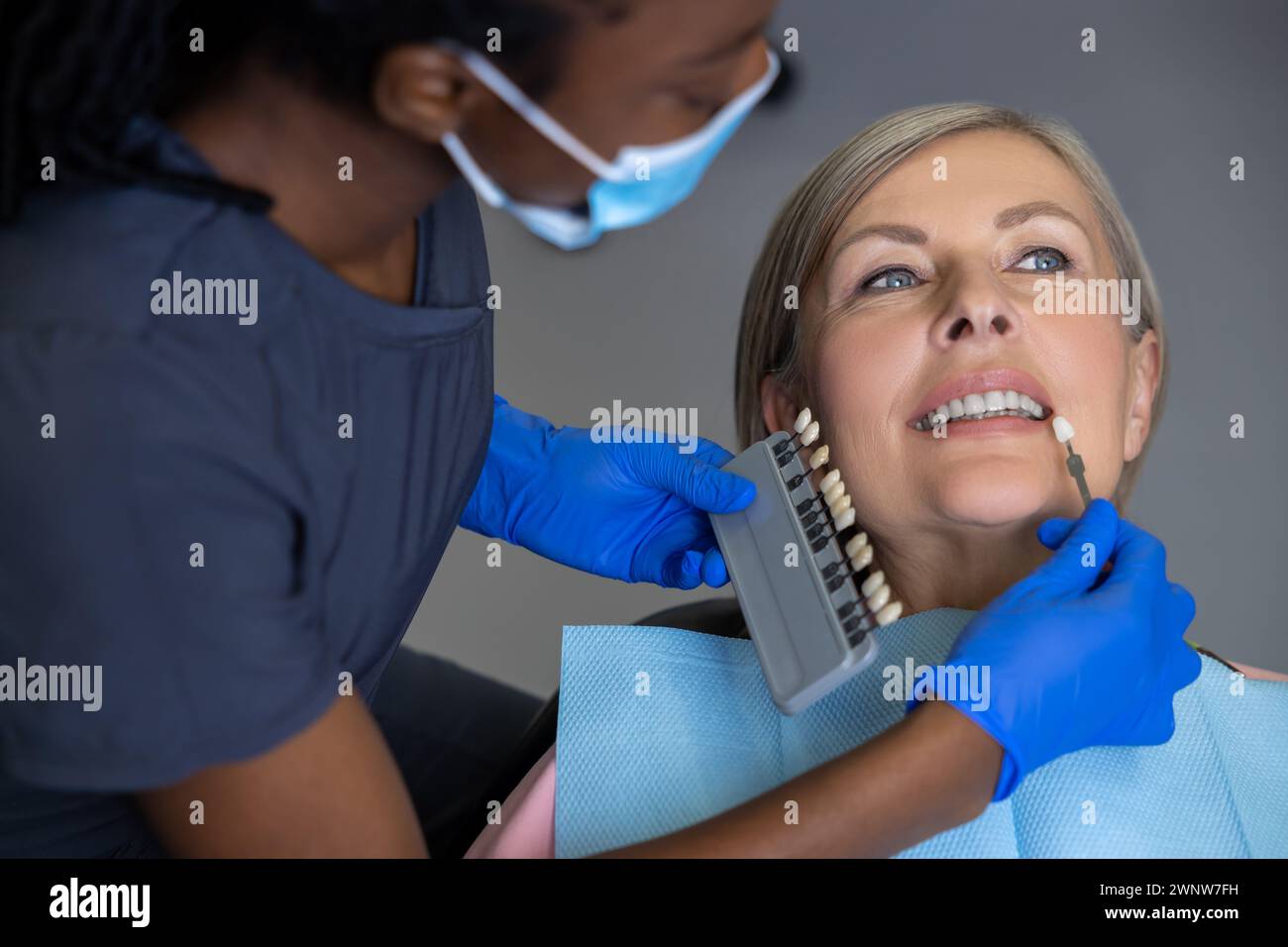 Woman patient with doctor orthodontist choosing the shade of dental ...