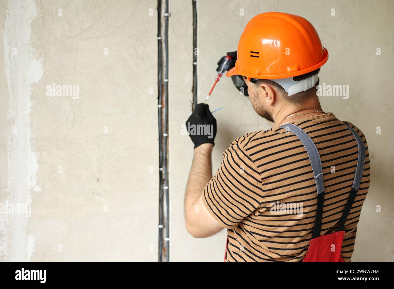 male electrician hands checks presence of electrical voltage in socket ...