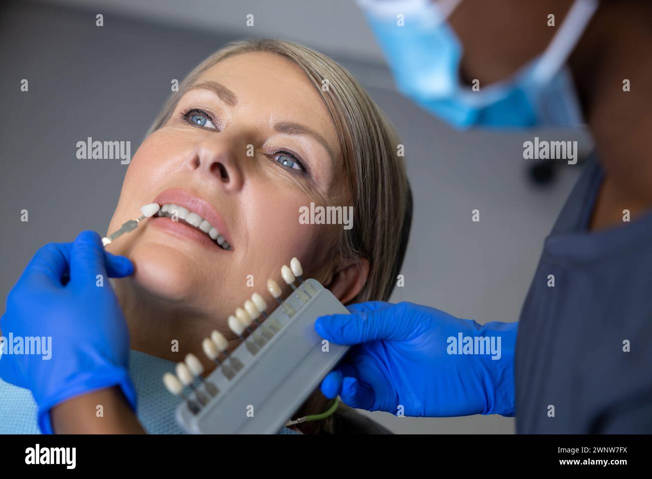 Woman dentist holding dental teeth shade guide chart choosing right ...