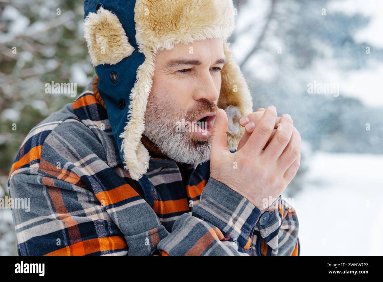 Mature man in warm hat warming his hands with his breath Stock Photo ...
