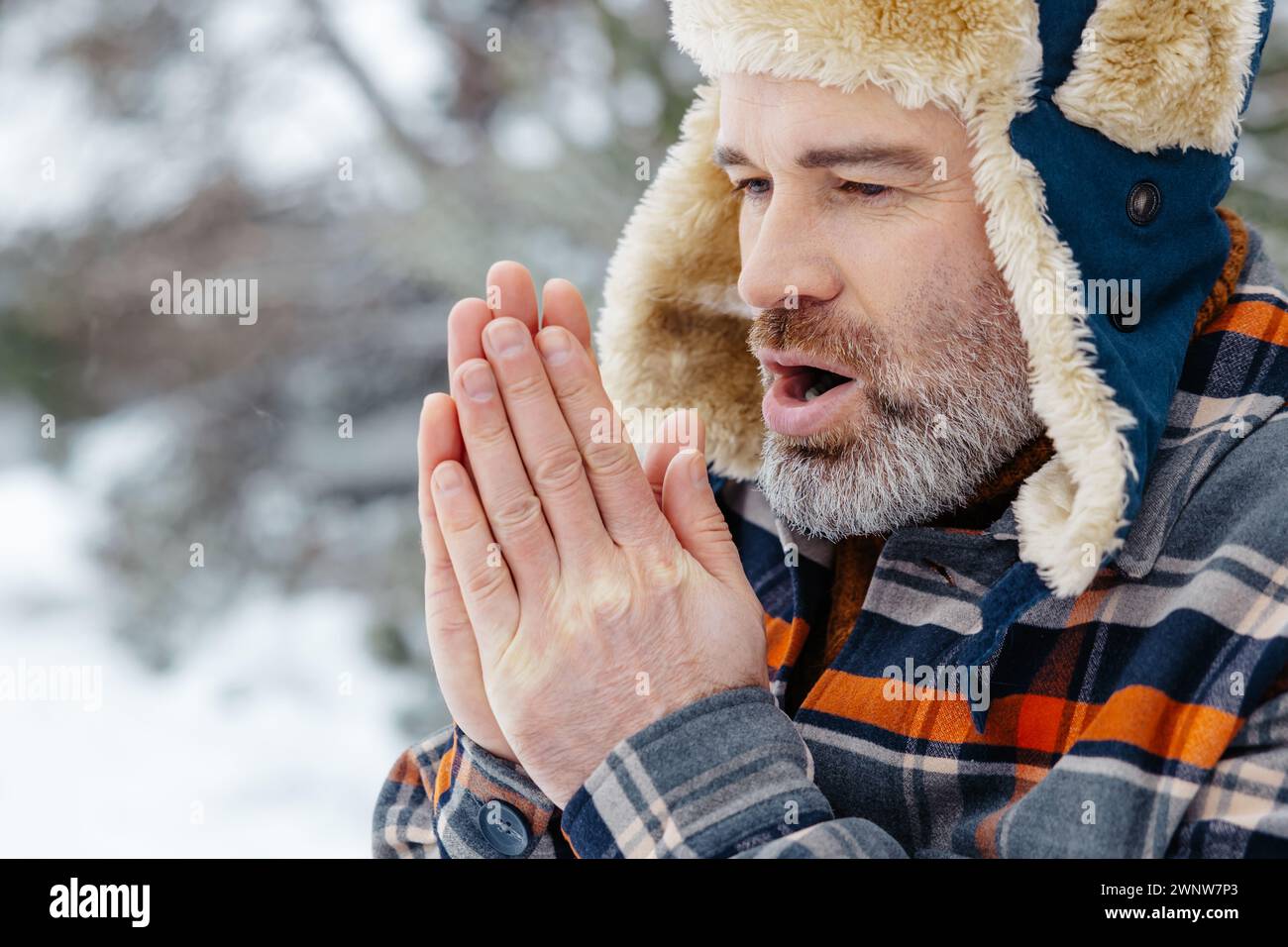 Mature man in warm hat warming his hands with his breath Stock Photo ...