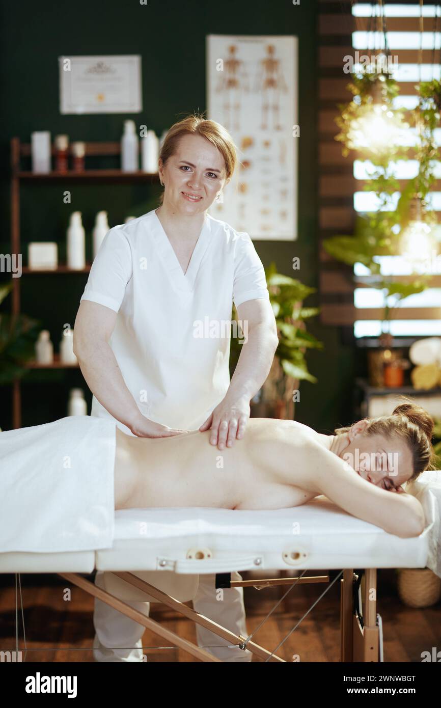 Healthcare time. smiling medical massage therapist in massage cabinet do a massage therapy on ...
