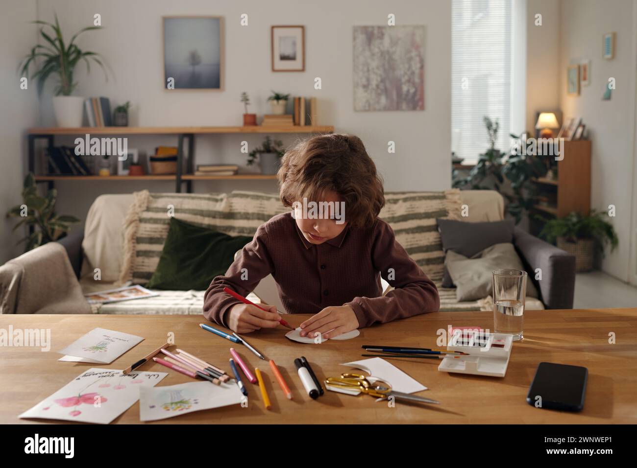 Diligent boy with red crayon creating handmade postcard for his mother ...