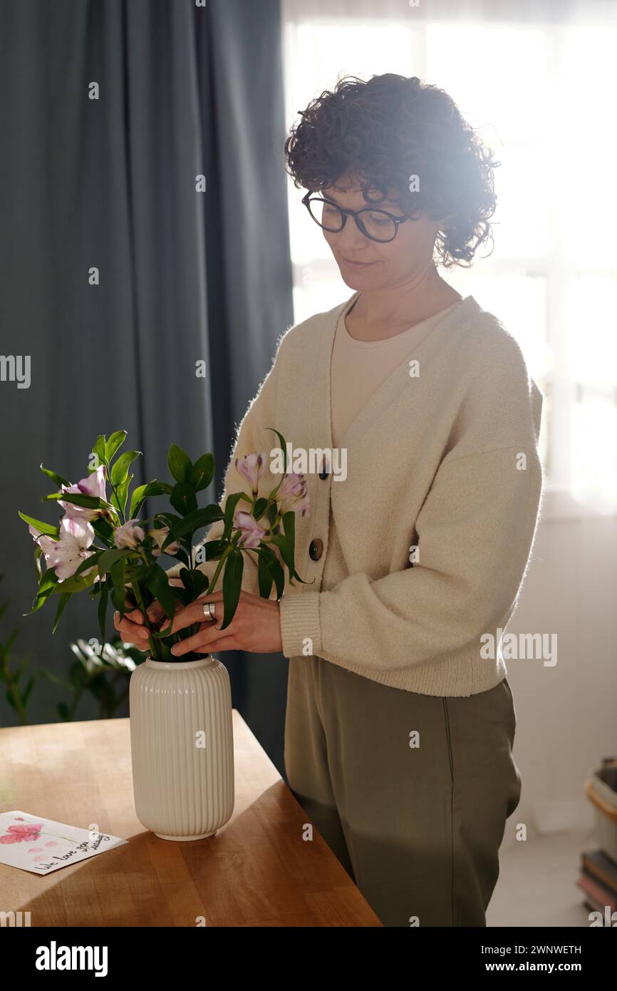 Young woman in quiet luxury attire putting bunch of fresh flowers in ...