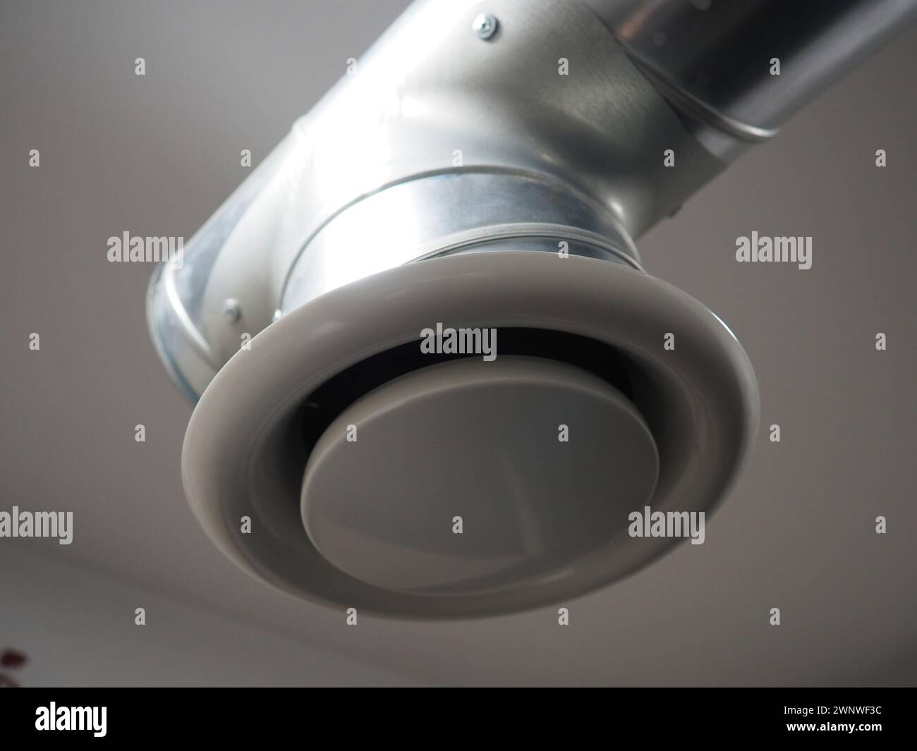 Extractor hood in a public toilet. Round metal pipe with gray air ...