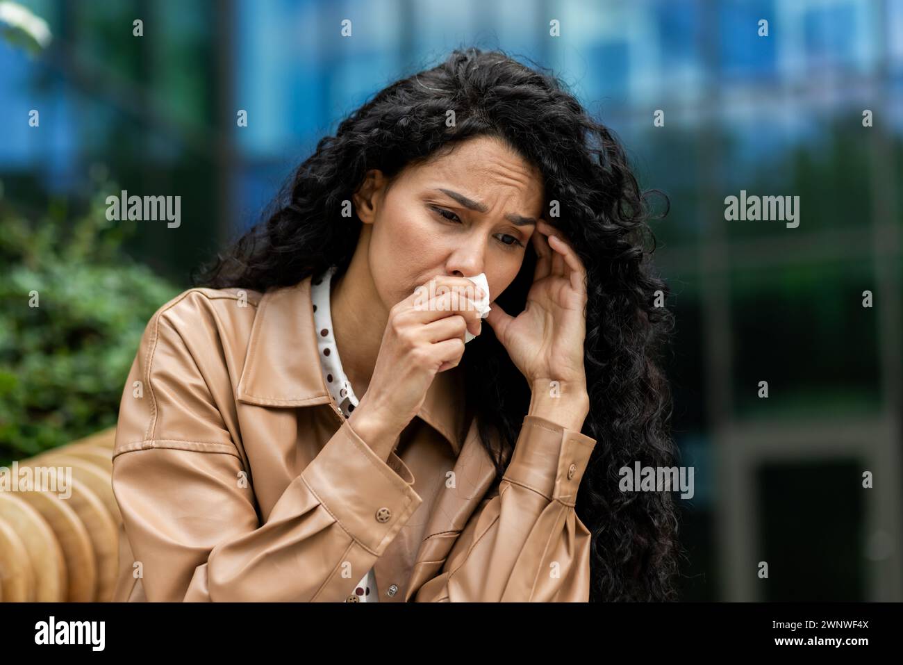 A distressed businesswoman in professional attire is sitting outside ...