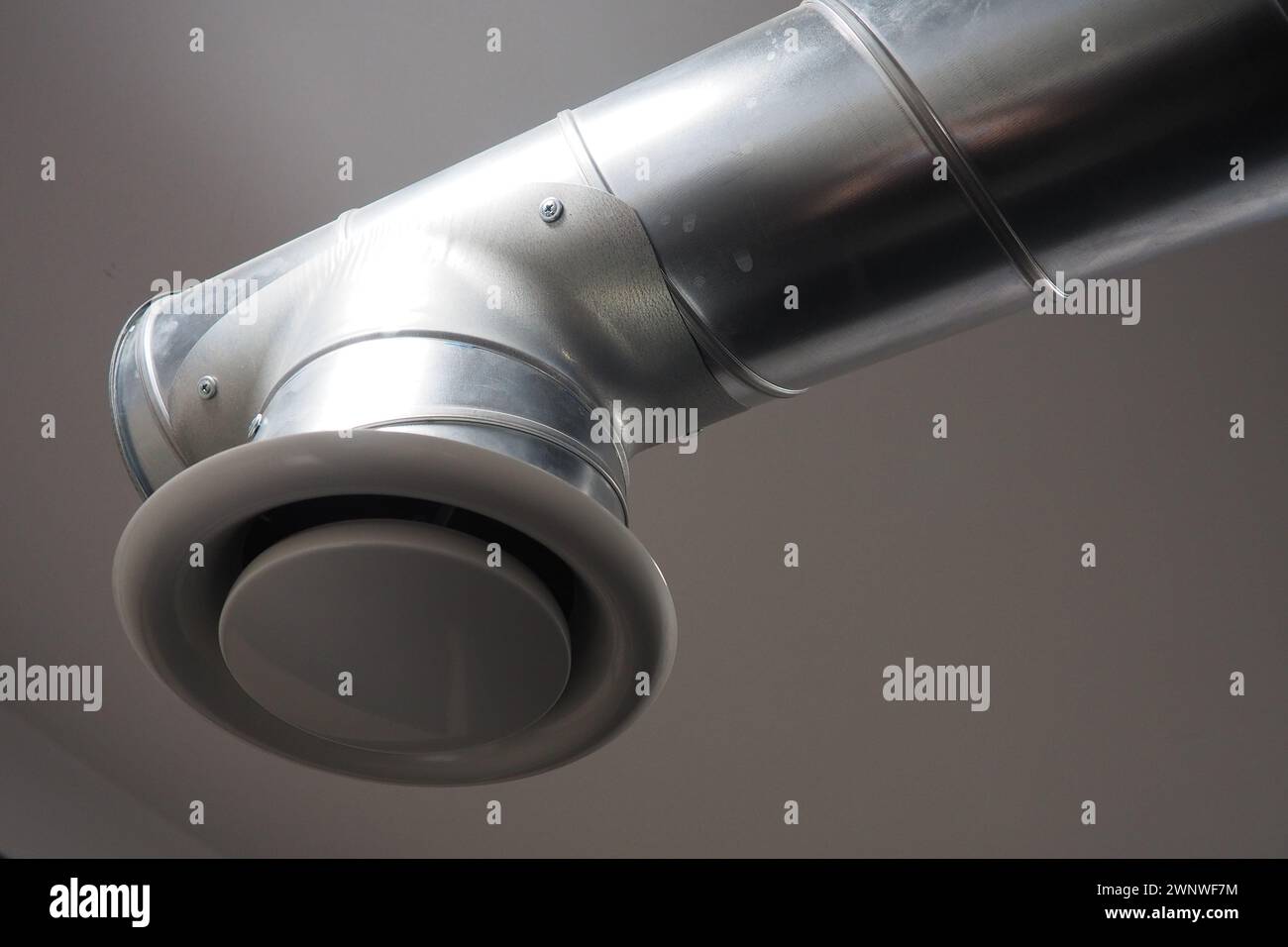 Extractor hood in a public toilet. Round metal pipe with gray air ...