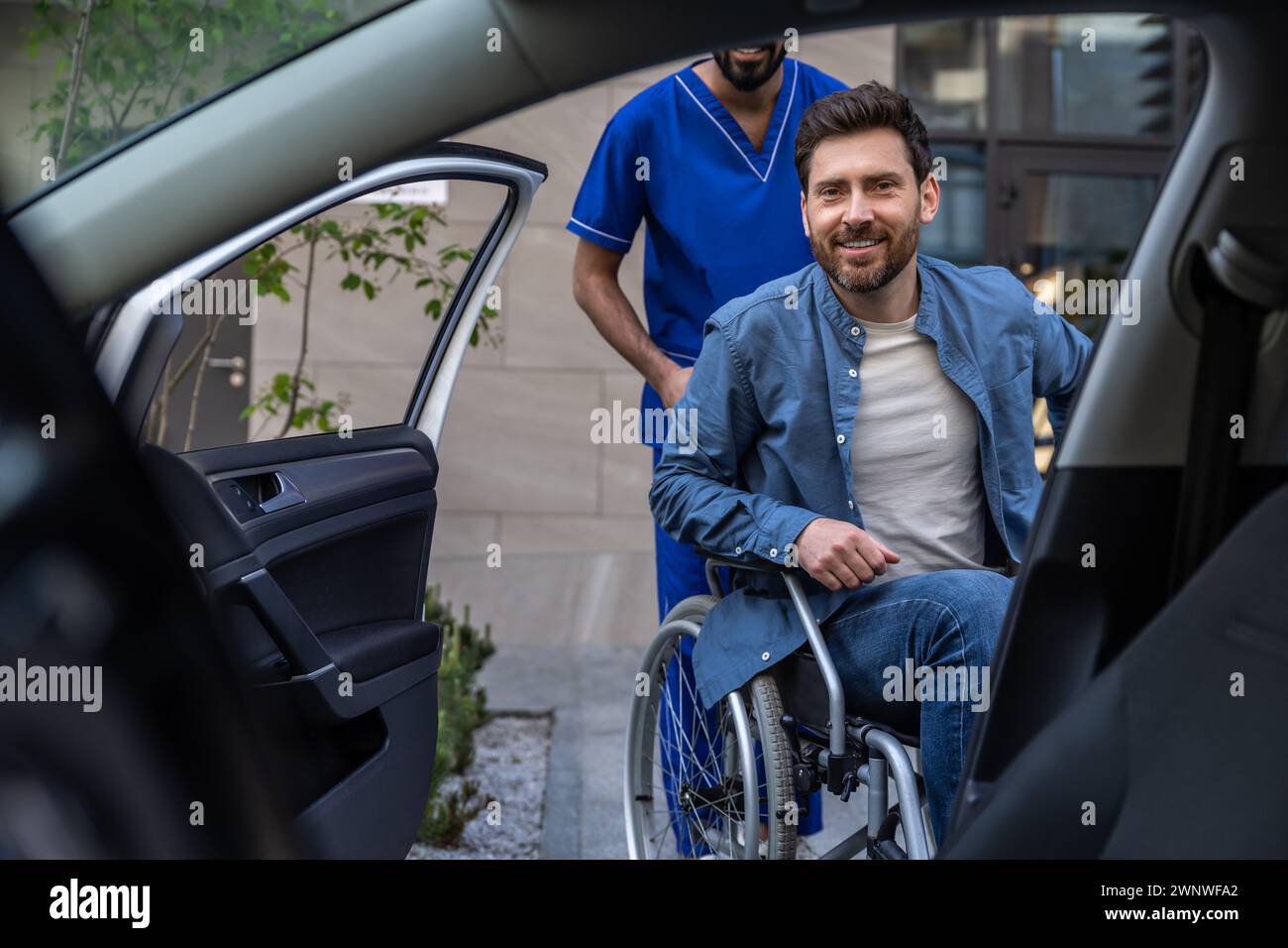 Disabled man getting on a car, male nurse helping him Stock Photo - Alamy