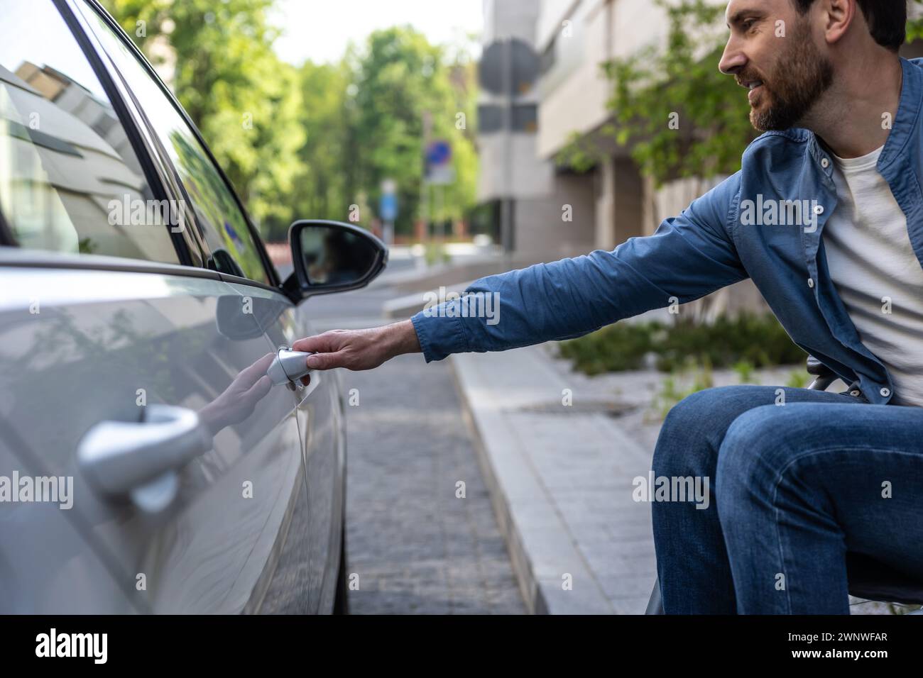 Disabled man in a wheelchair getting in a car Stock Photo - Alamy