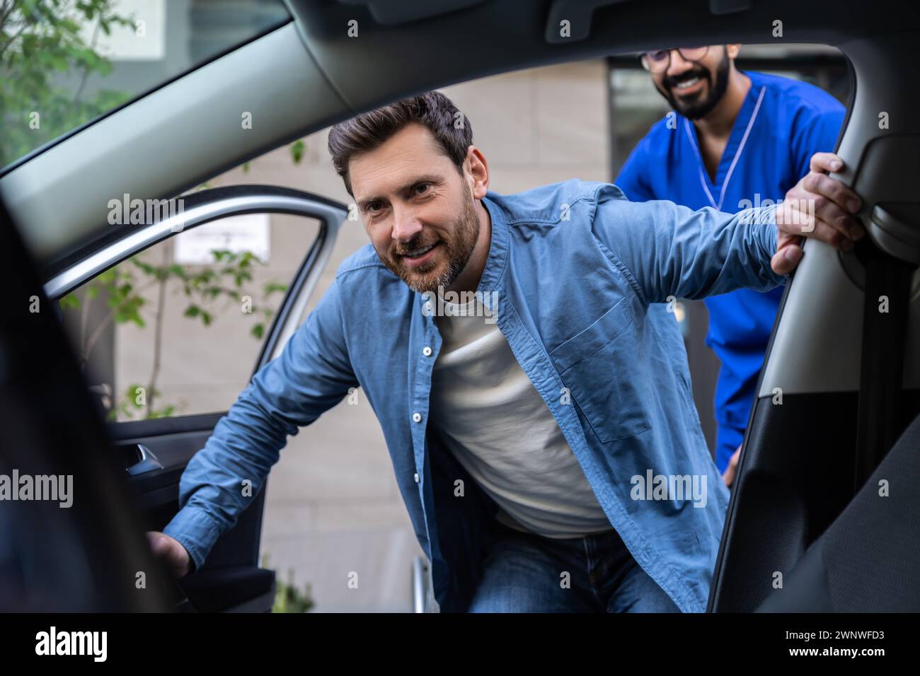 Disabled man getting on a car, male nurse helping him Stock Photo - Alamy