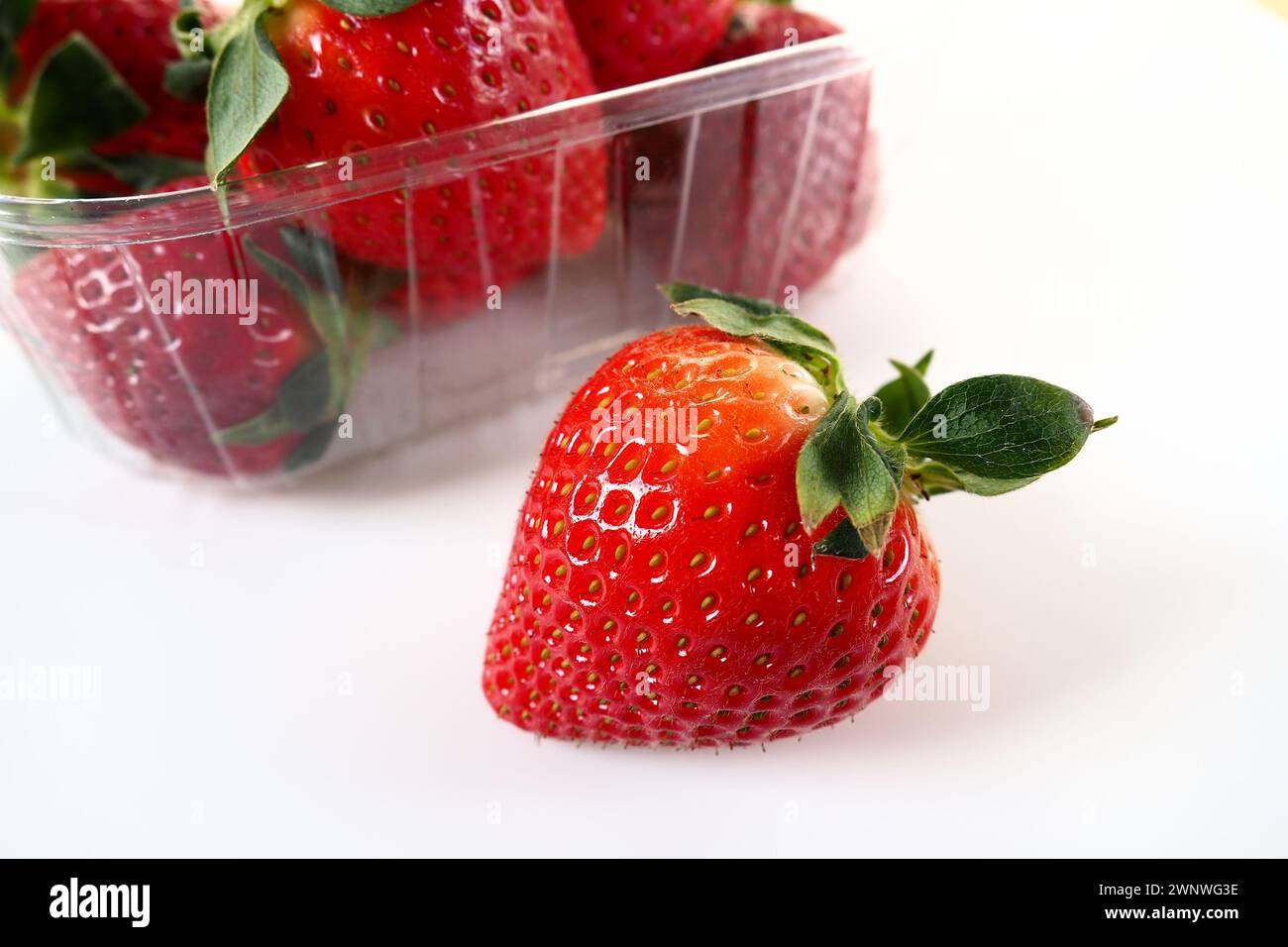 Ripe strawberries in a plastic package on a white background. Delicious ...