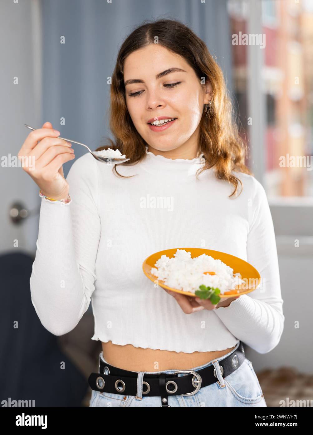 Emotional young woman eating rice at home Stock Photo - Alamy