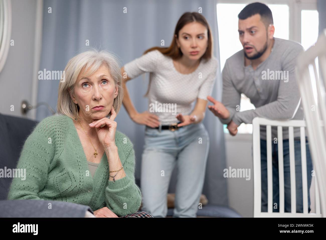Senior woman ignoring adult couple scolding her Stock Photo - Alamy