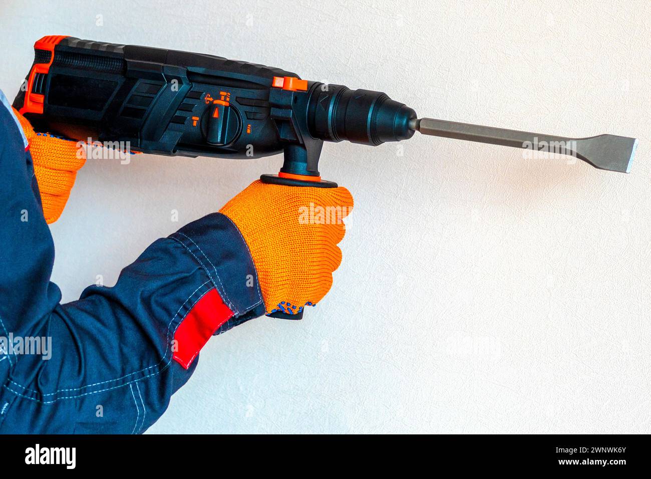 workman with a rotary hammer. Hands in protective gloves with hammer drill perforator. Copy ...