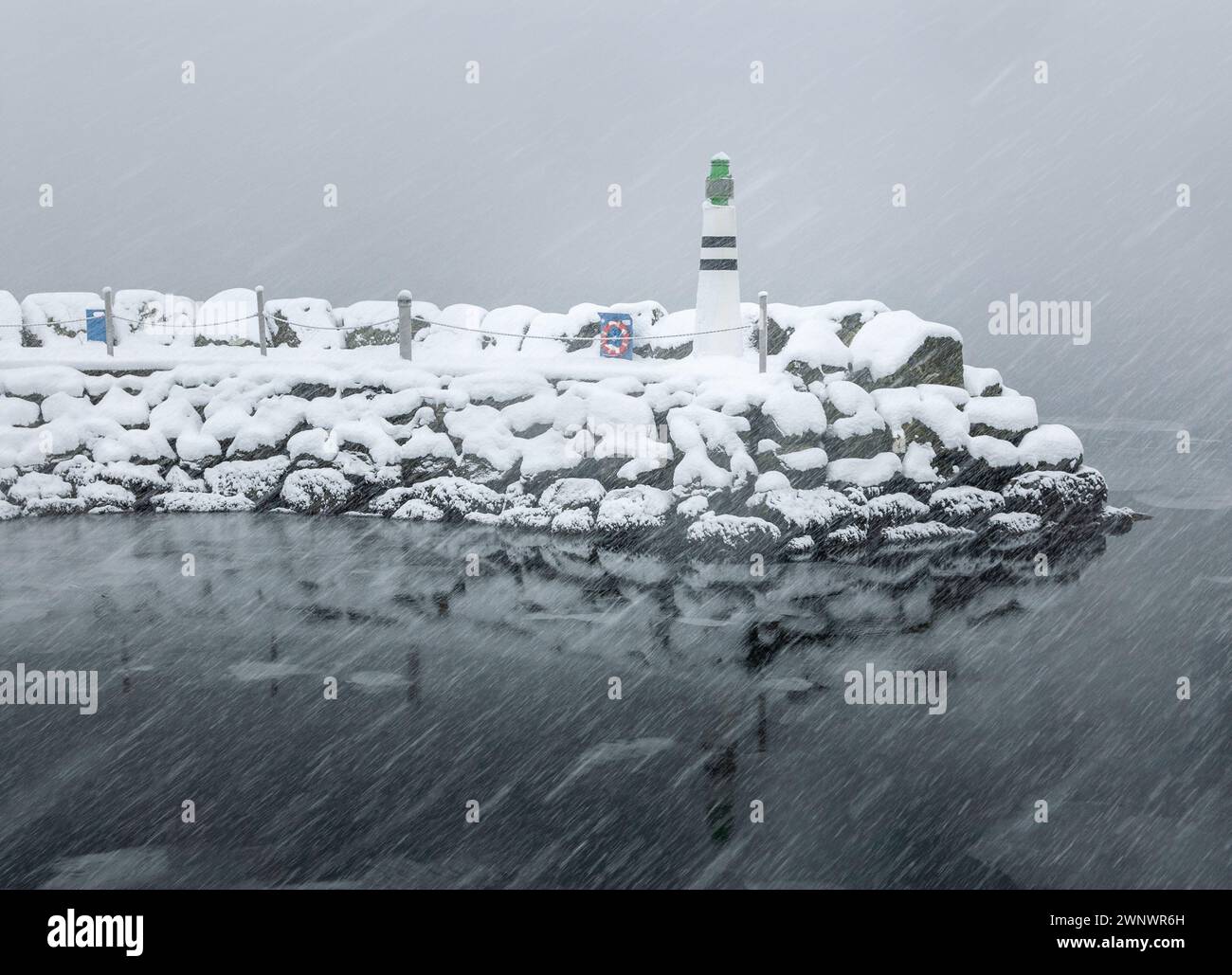 A lighthouse stands resilient as snow covers the surrounding landscape ...