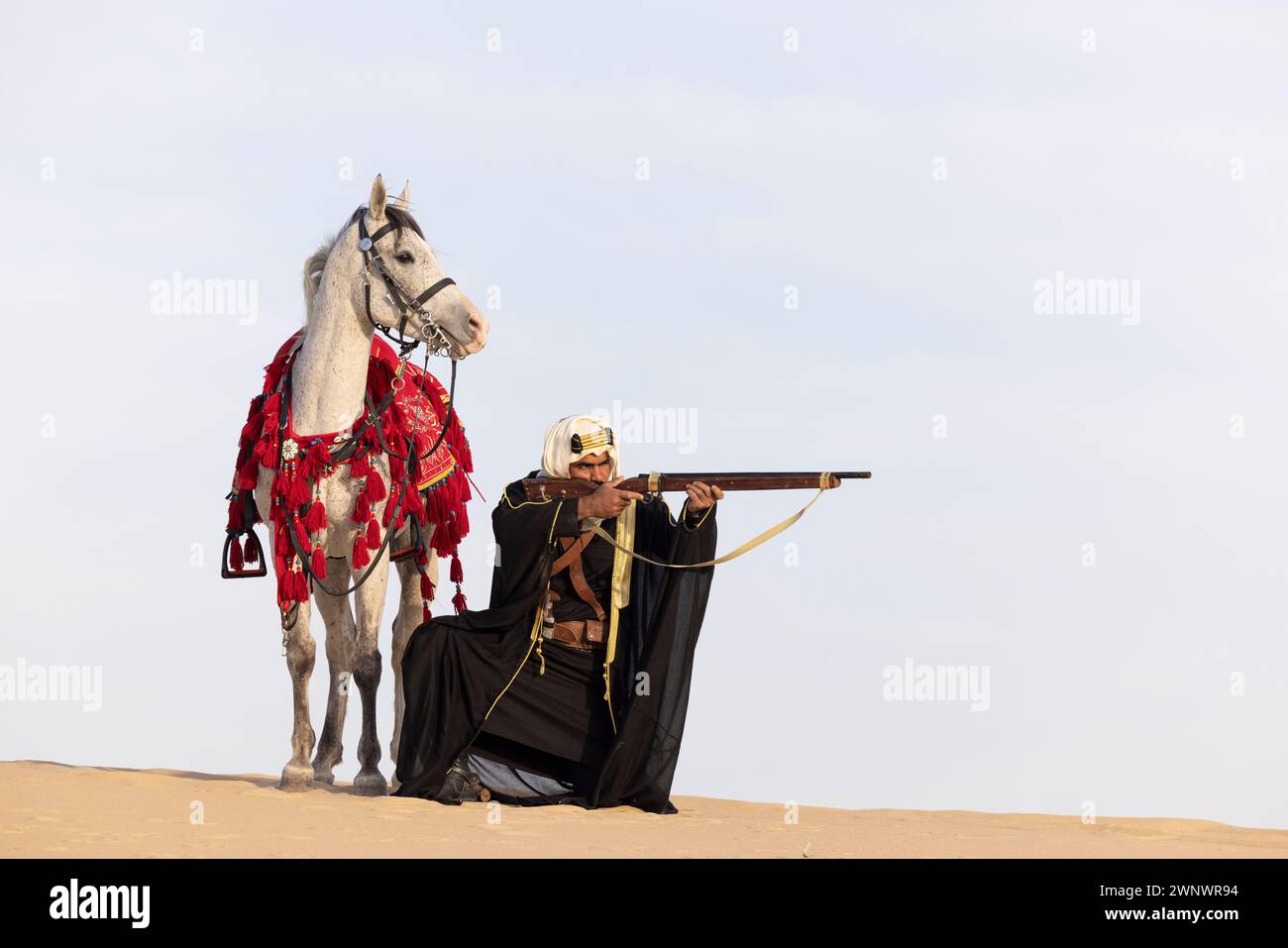Saudi man hunting in the desert, aiming his rifle Stock Photo - Alamy