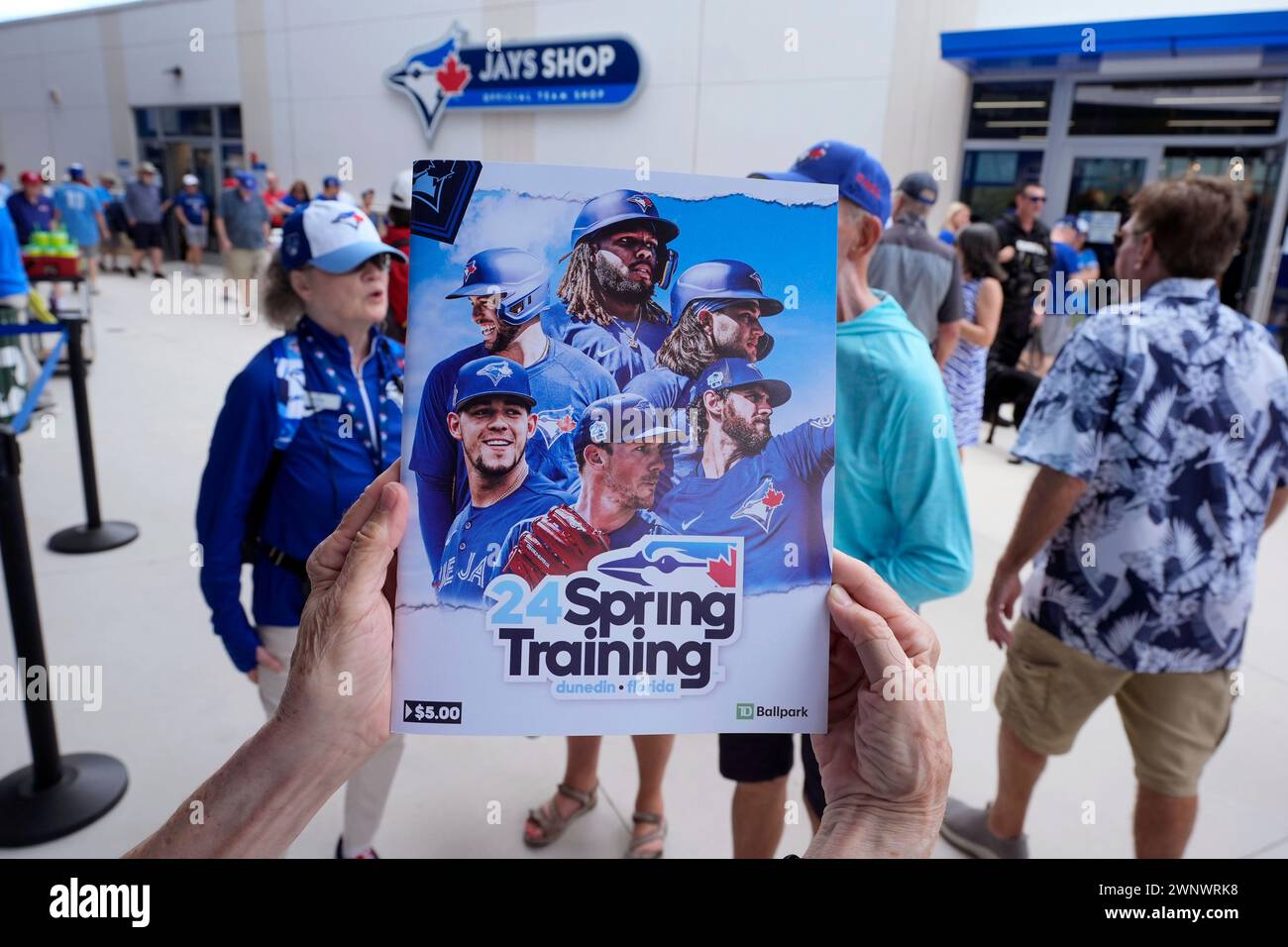 A vendor holds a program before a spring training baseball game between ...