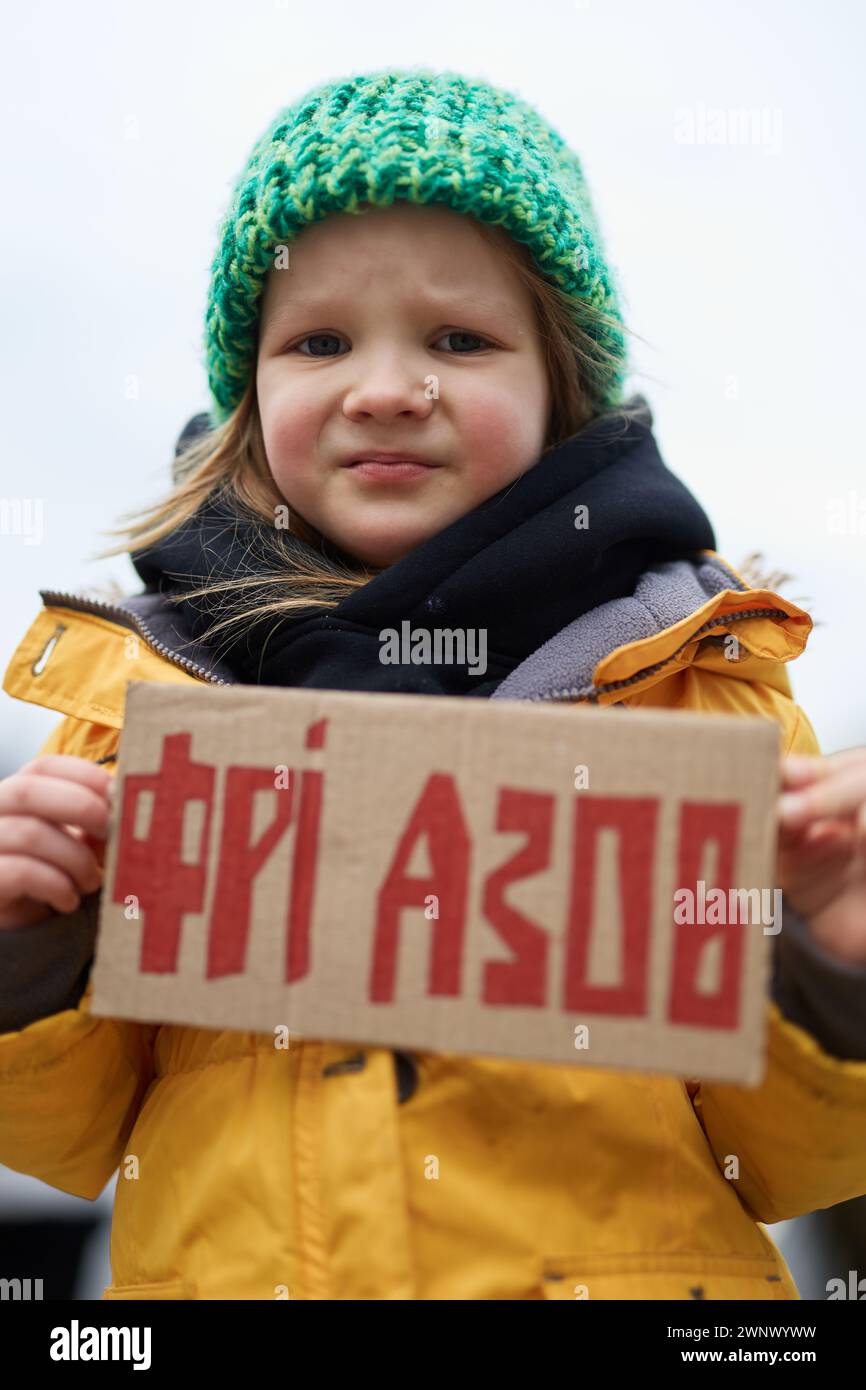 Sad little girl posing with a banner "Free Azov" on a peaceful ...