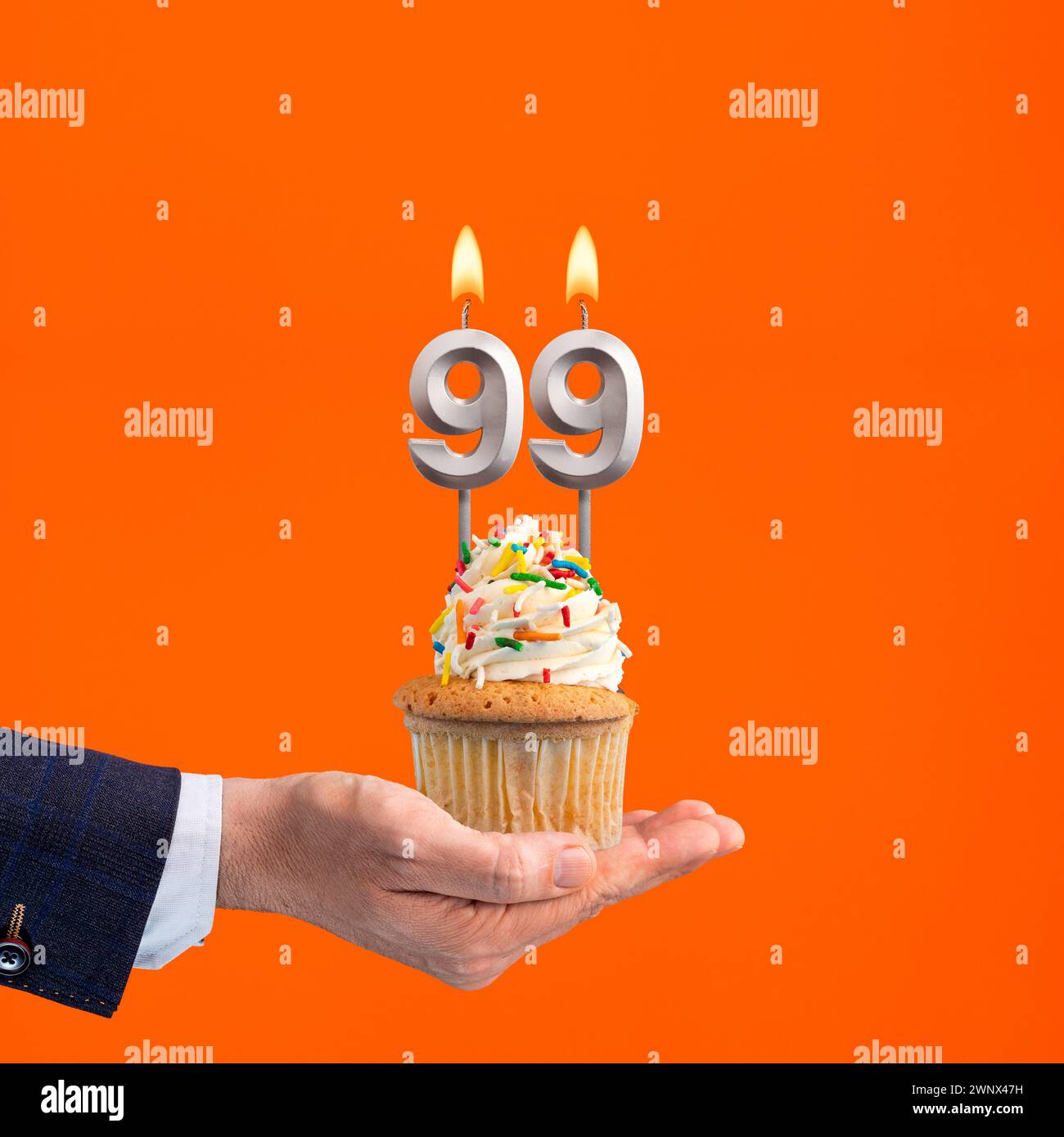 Hand holding birthday cupcake with number 99 candle - background orange ...