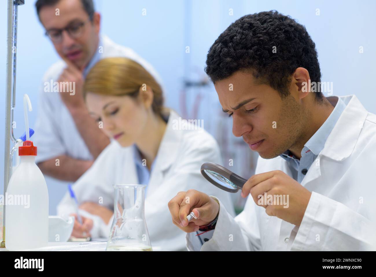 young male student using magnifying glass in science lab Stock Photo ...