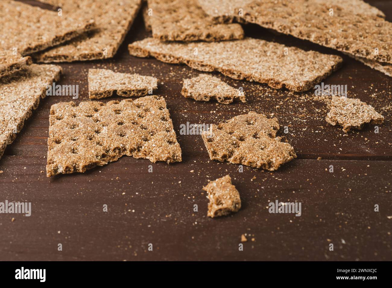 Pieces of crispy wheat, rye and corn flatbread crackers on wooden table ...