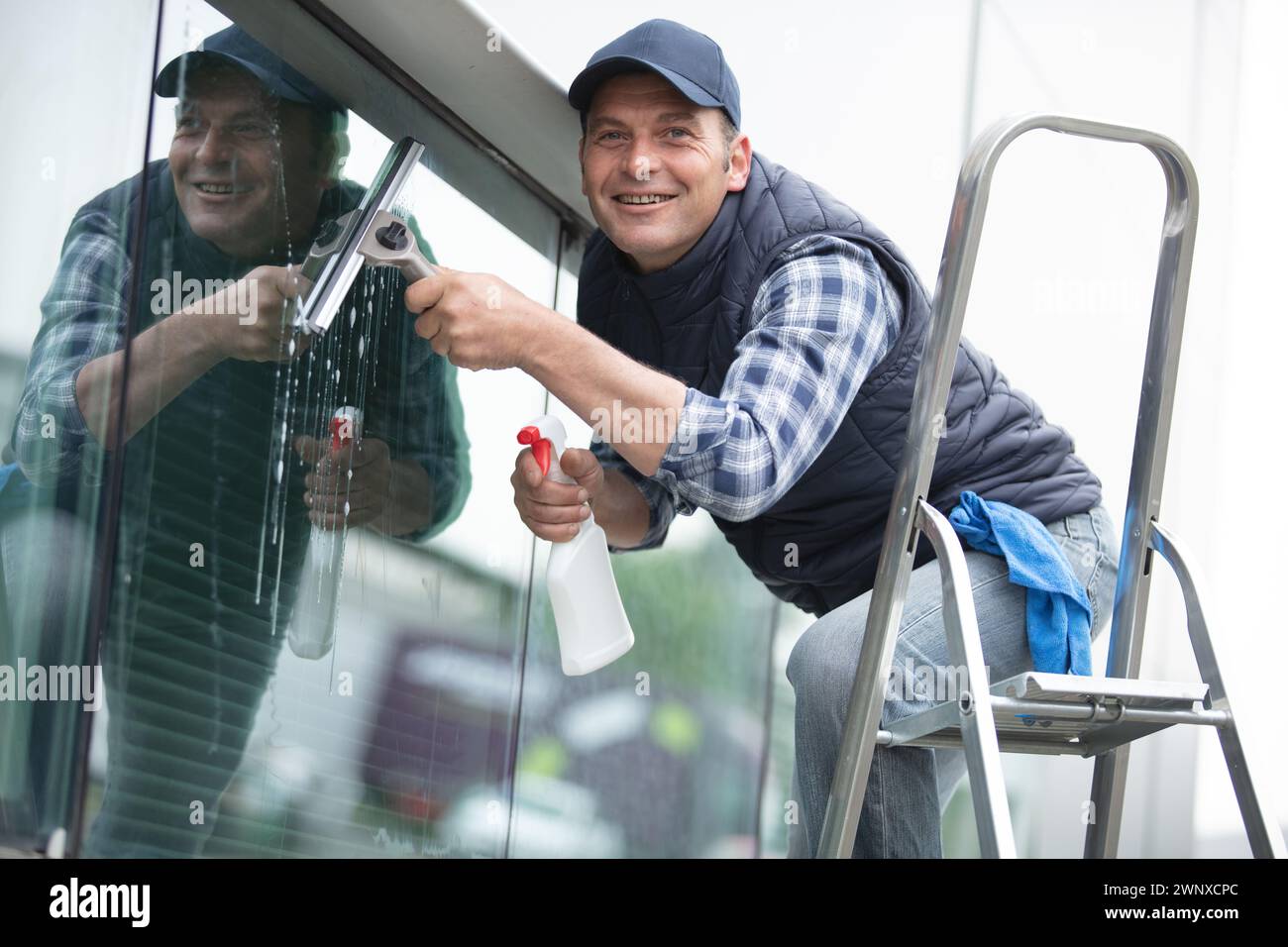man on stepladder washing window outdoors Stock Photo - Alamy