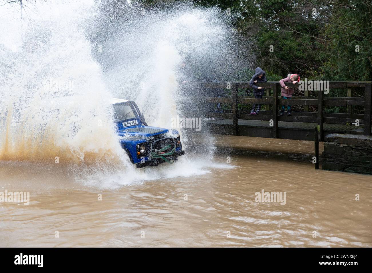 20/02/22 Land Rover Defender splashes young spectators. As heavy rain ...