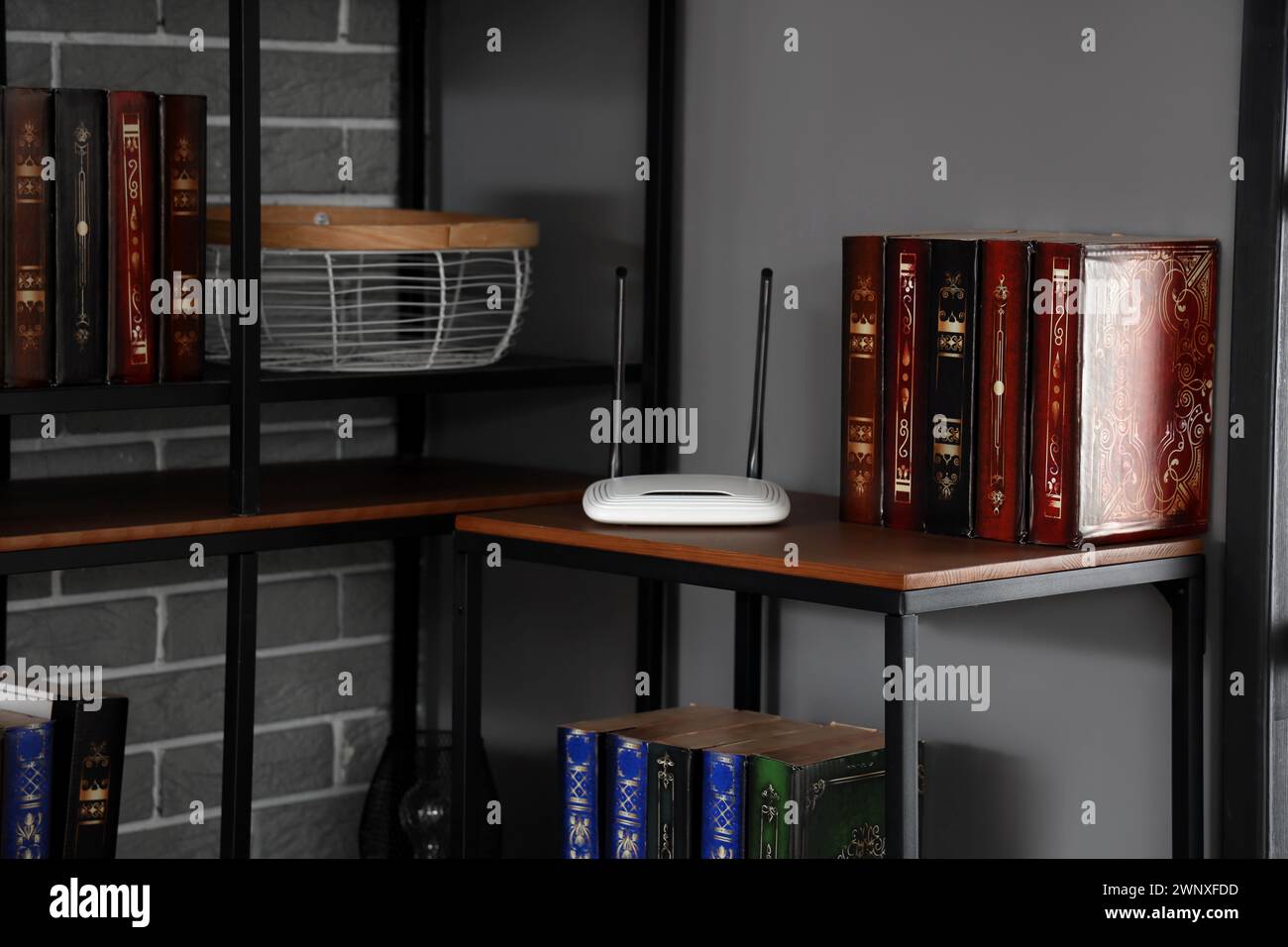Modern wi-fi router on bookshelf in dark room Stock Photo - Alamy