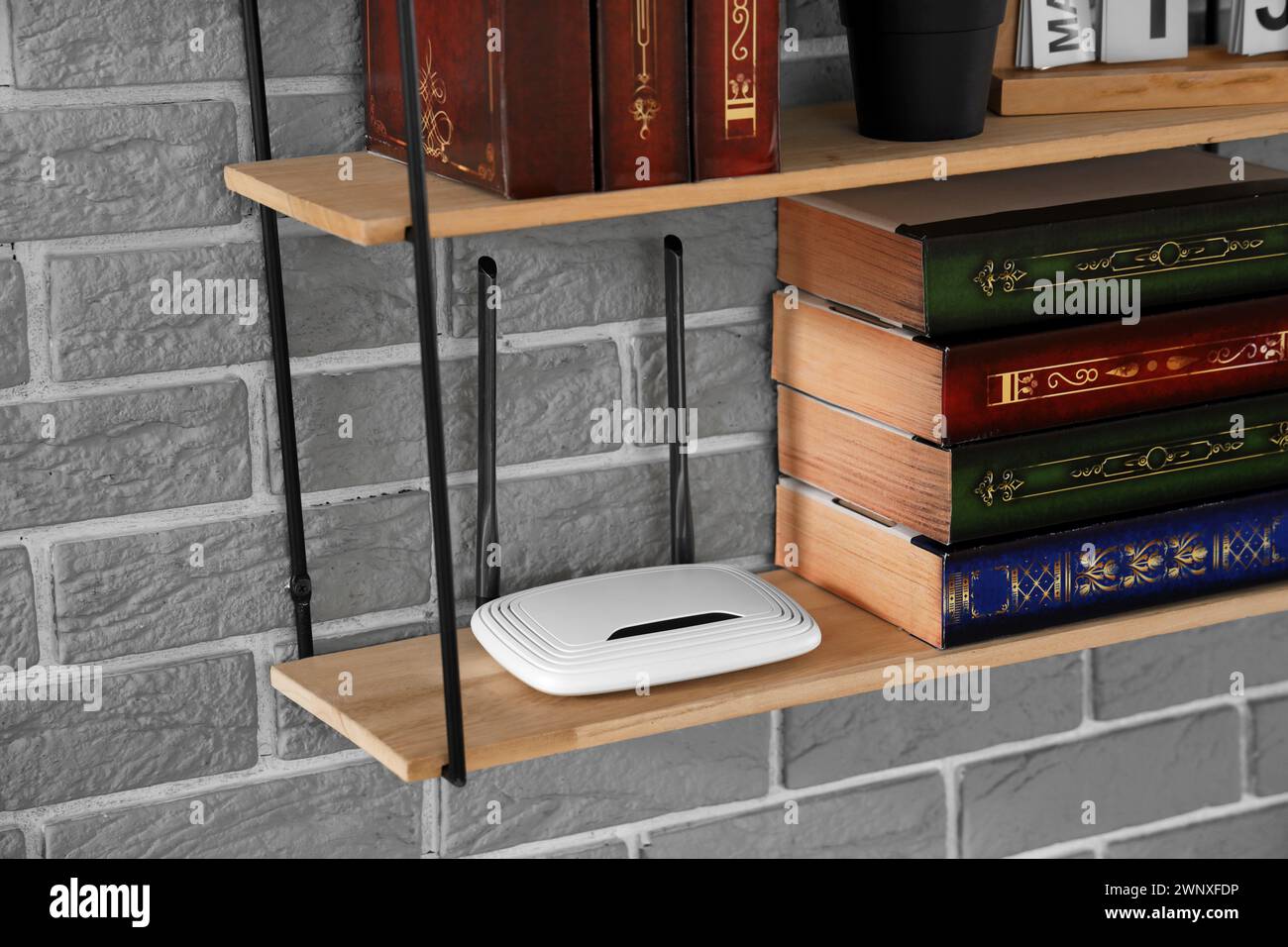 Bookshelf with modern wi-fi router on grey brick wall Stock Photo - Alamy
