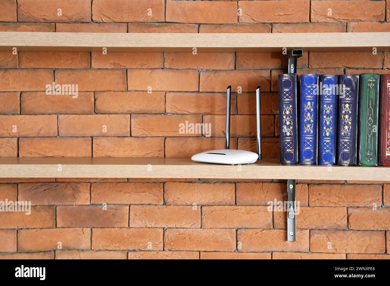 Shelf with books and wi-fi router on brick wall Stock Photo - Alamy