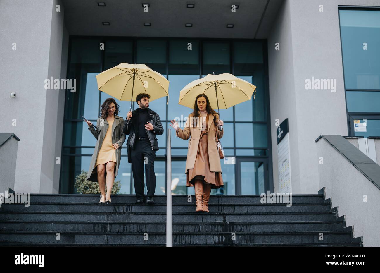 A trio of corporate colleagues exits a modern building under open ...